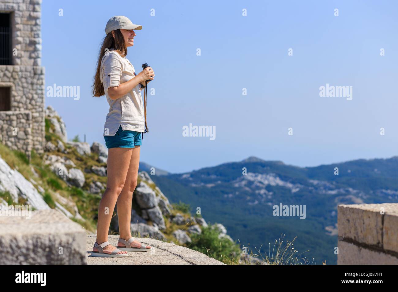 Young woman watching mountain landscape through binoculars at the view ...