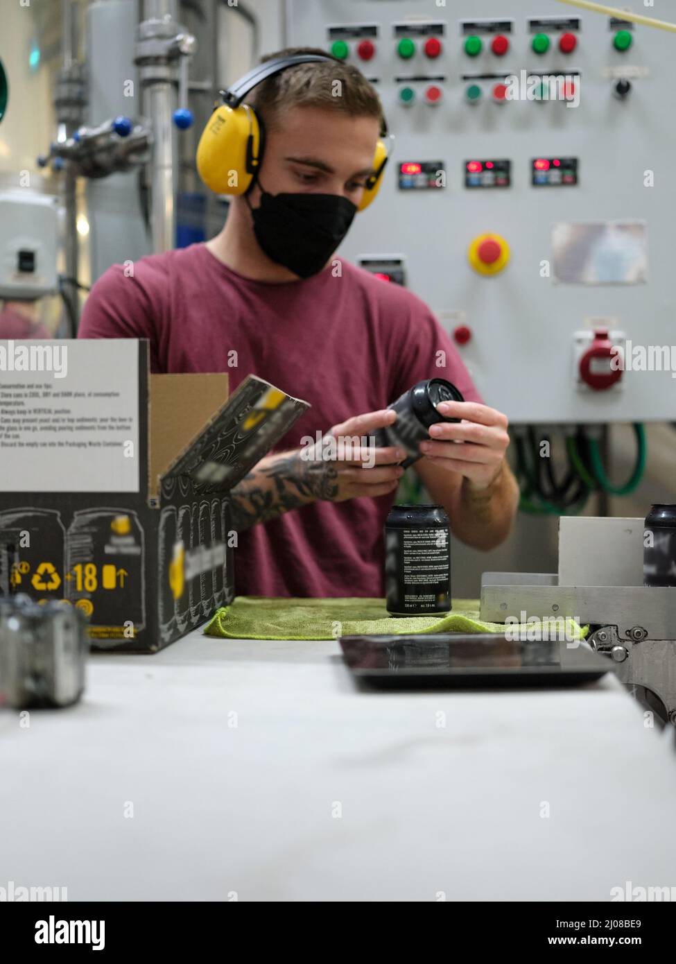Worker reading the label on a beer can before packing it for shipment ...