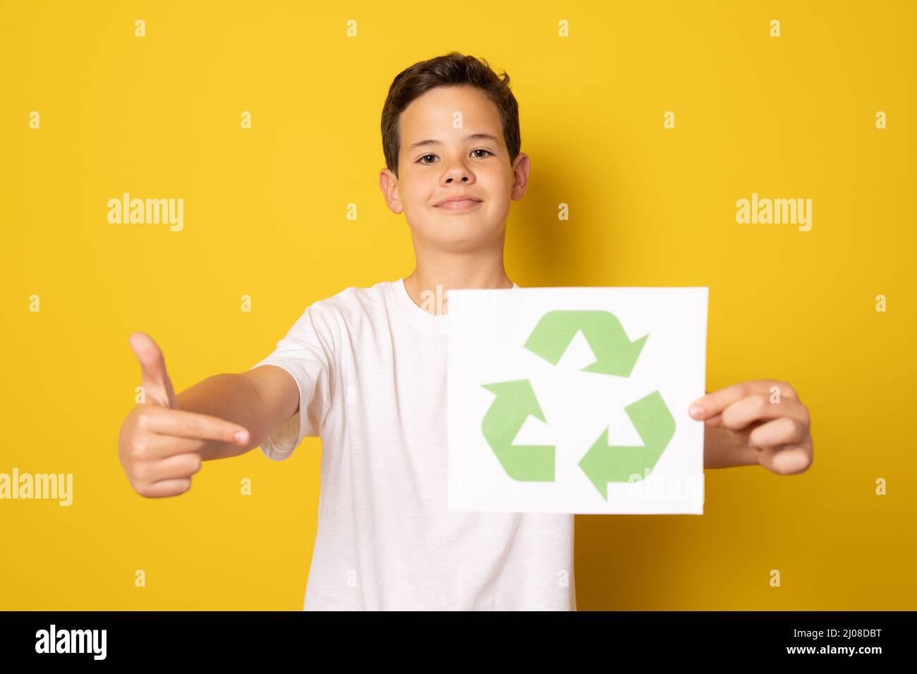 Little boy holding recycle symbol standing isolated over yellow ...