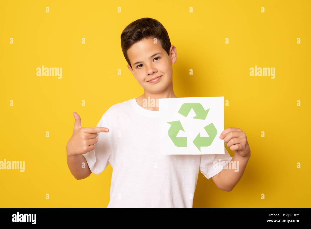 Little boy holding recycle symbol standing isolated over yellow ...