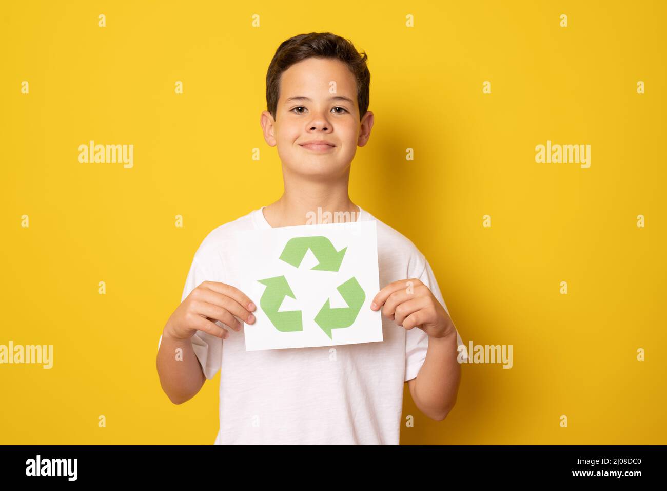 Little boy holding recycle symbol standing isolated over yellow ...