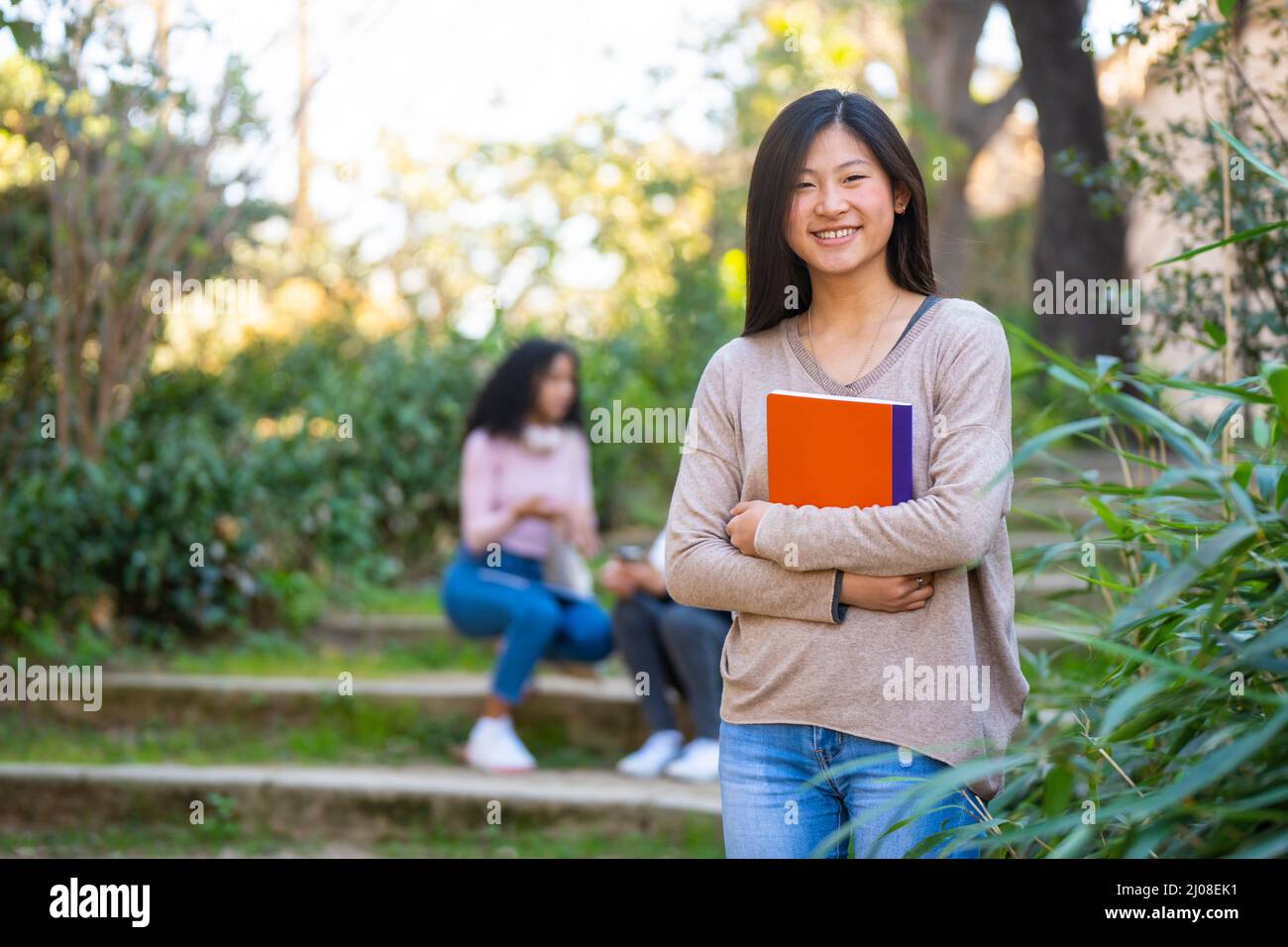 Young asian female student smiling and looking to the camera with a ...