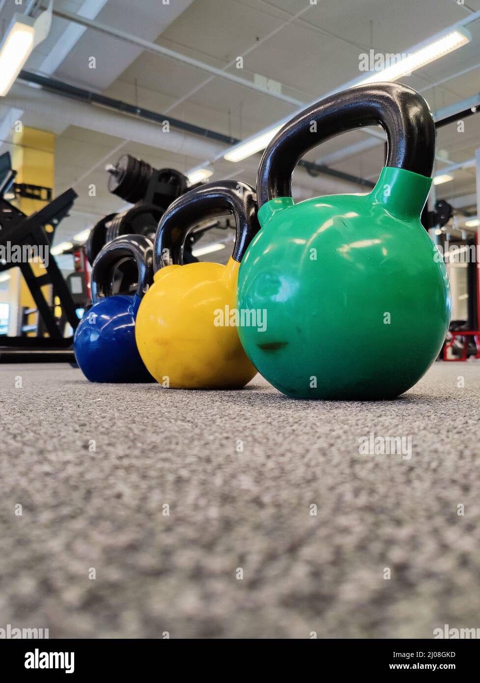 A vertical closeup of colorful dumbbells on the ground in a gym Stock ...