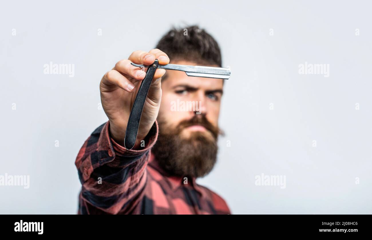 Man in barbershop. Handsome bearded hairdresser is holding a straight ...