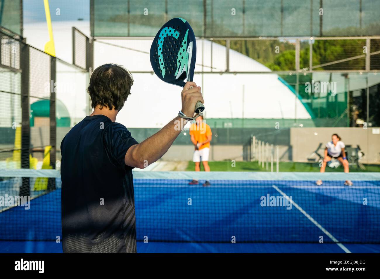 Mixed padel match in a blue grass padel court - Beautiful girl and ...