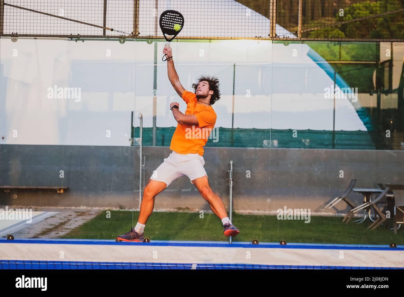 Padel match in a blue grass padel court - Handsome boy player playing a ...