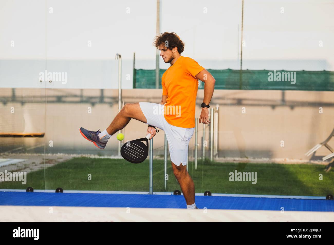 Padel match in a blue grass padel court - Handsome boy player playing a ...