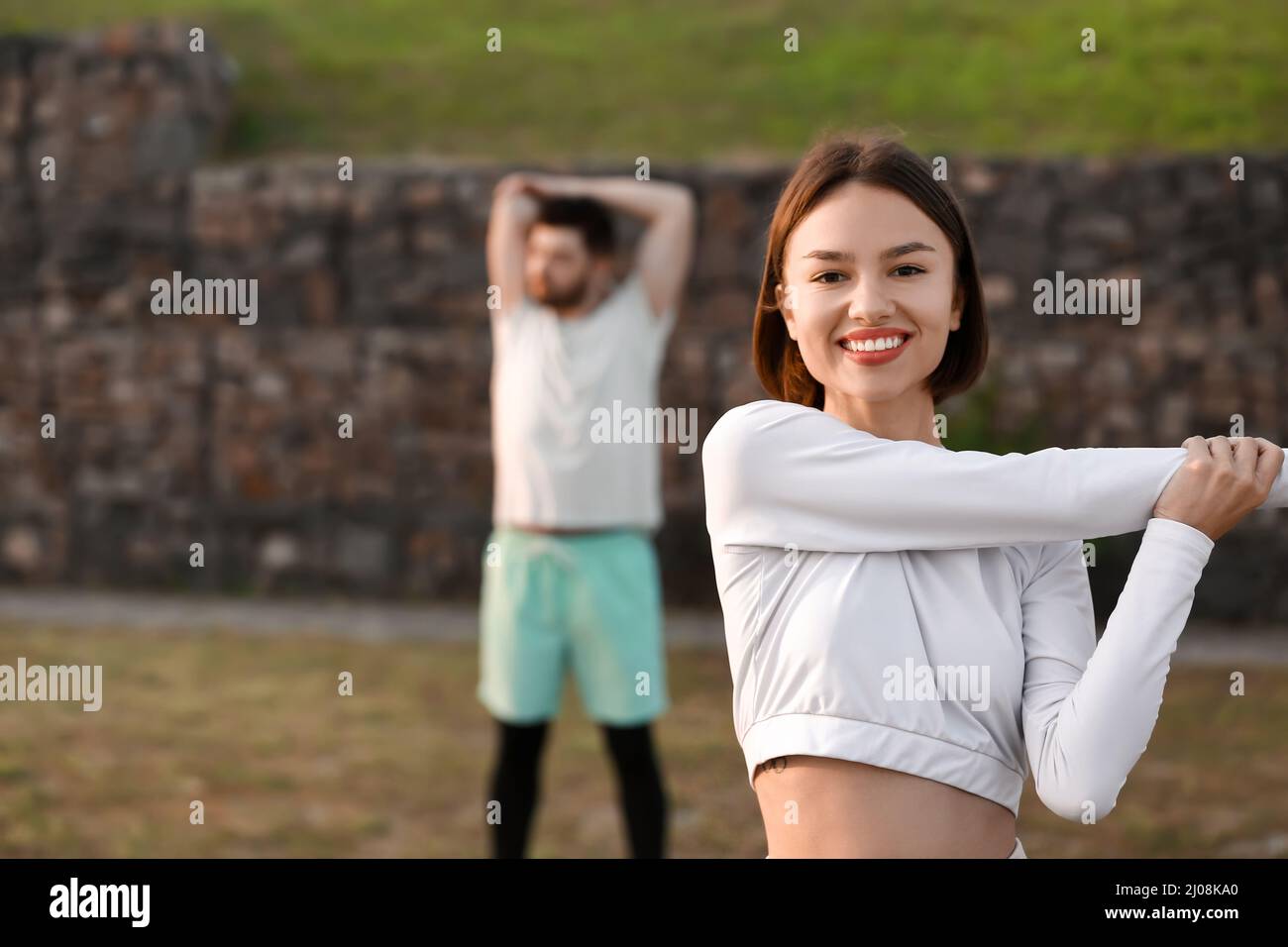 Sporty young woman stretching with her boyfriend outdoors Stock Photo ...