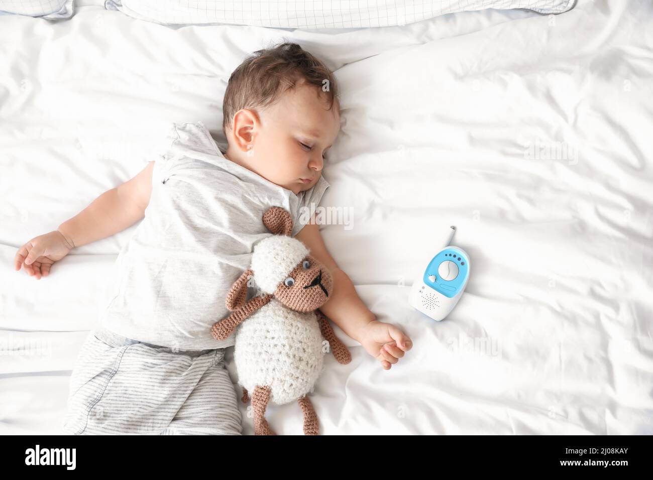 Adorable little child with toy and baby monitor sleeping on bed Stock ...
