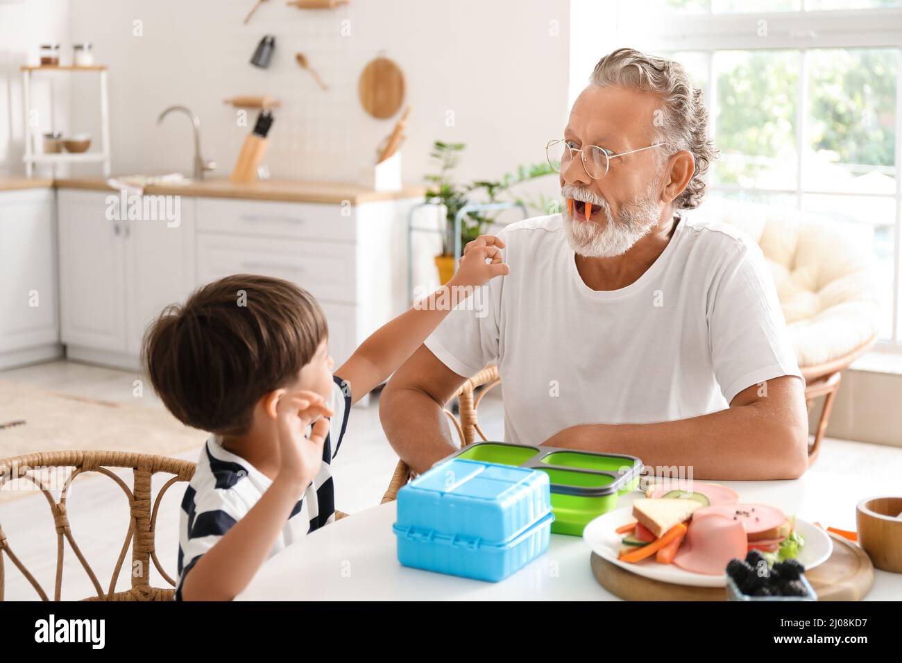 Little boy with his grandfather having fun while packing lunch boxes at ...
