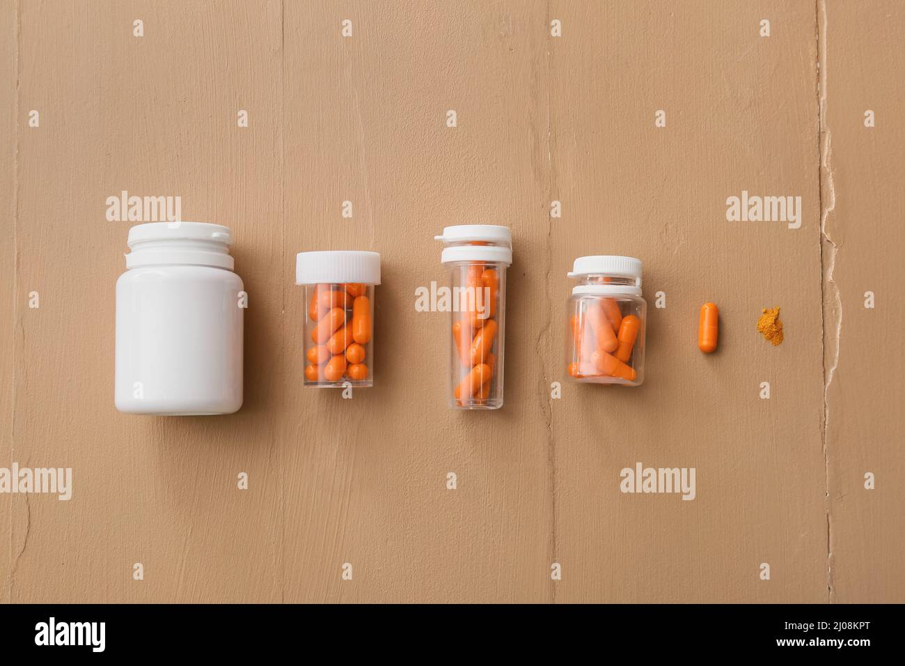 Bottles with turmeric powder capsules on color wooden background Stock ...