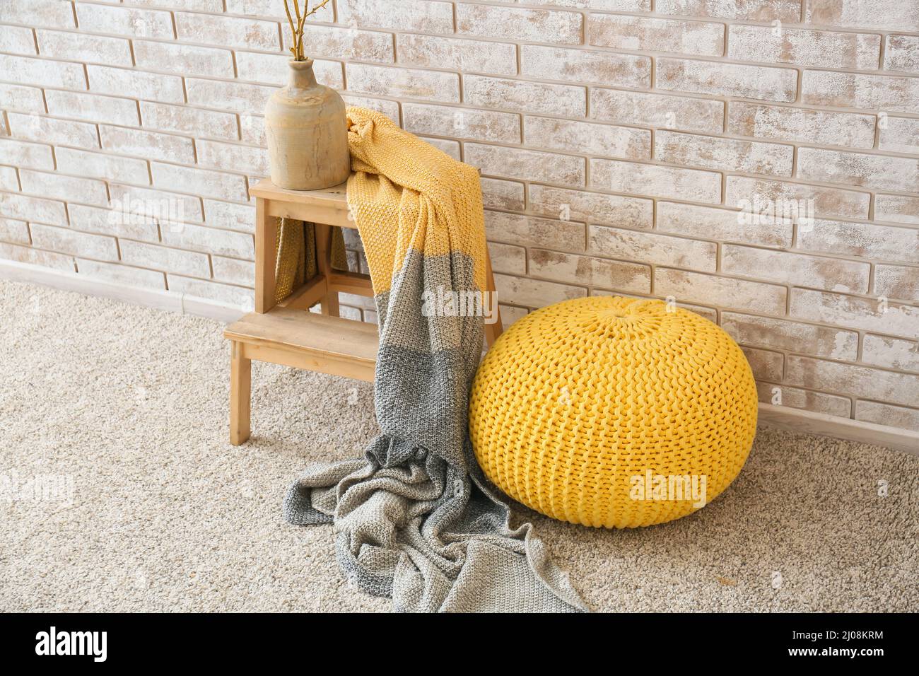 Modern pouf and step ladder near light brick wall in room Stock Photo ...