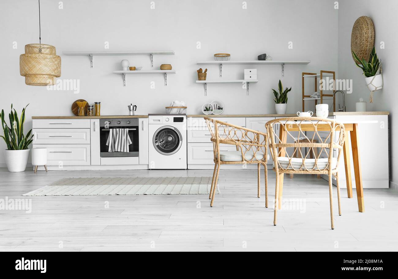 Interior of light kitchen with washing machine, white counters and ...