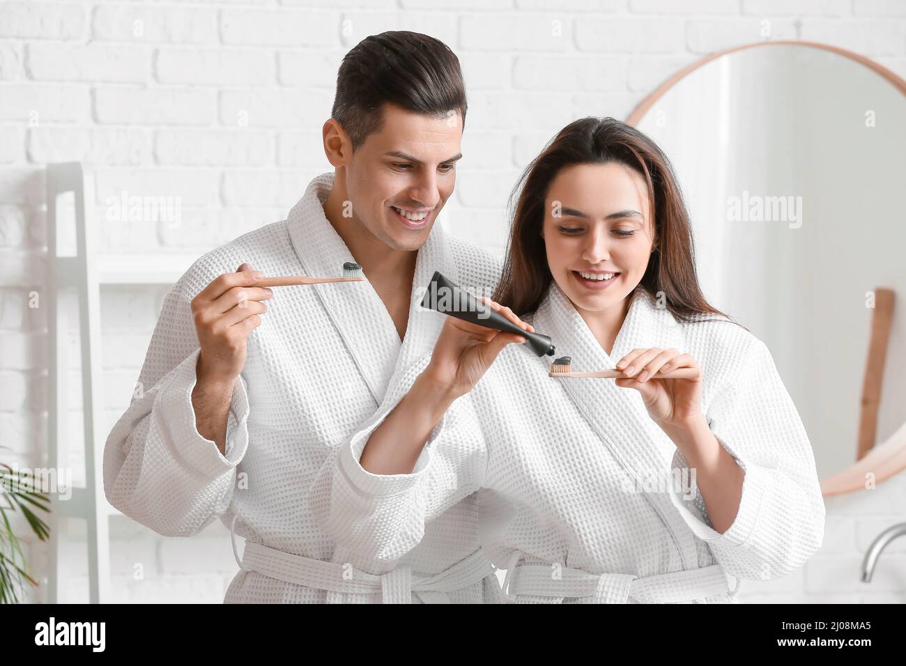 Young couple brushing teeth with activated charcoal tooth paste in ...