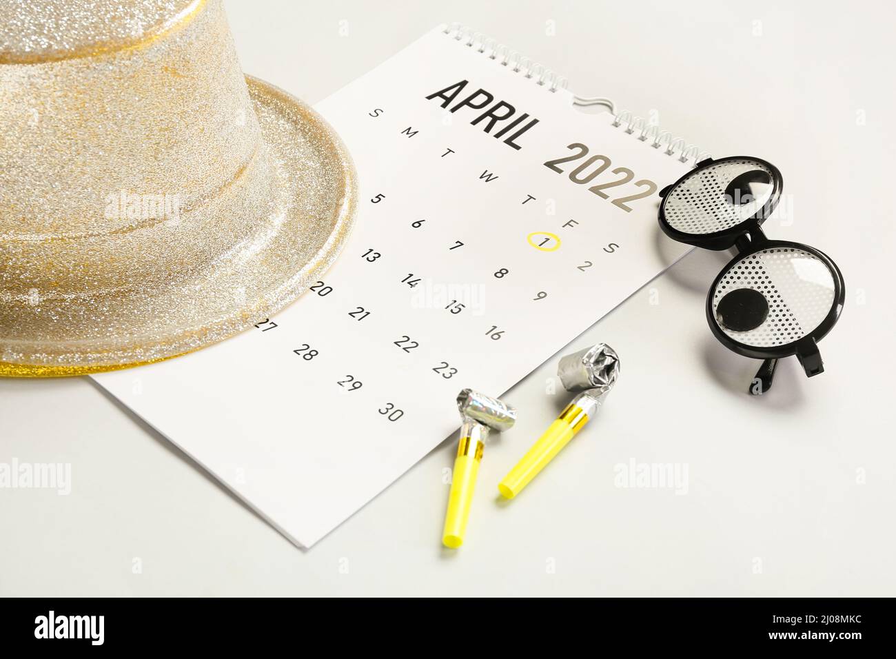 Calendar with marked date of April Fool's Day and party decor on light ...