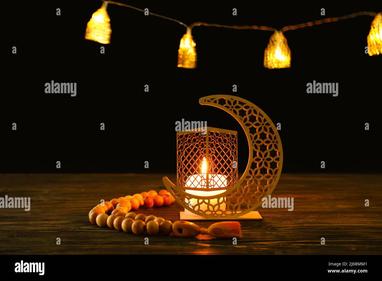 Arabic candle holder with glowing candle and tasbih on table against ...