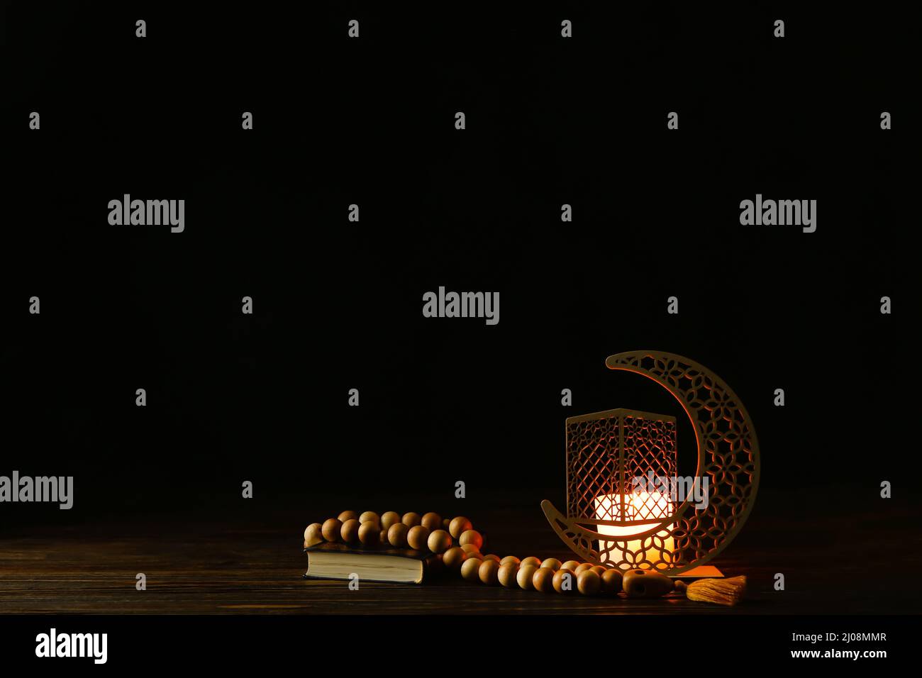 Arabic candle holder with glowing candle, Quran and tasbih on dark ...
