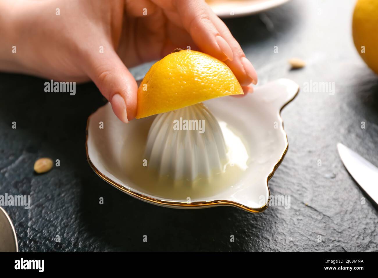 Woman squeezing fresh lemon on dark background Stock Photo - Alamy