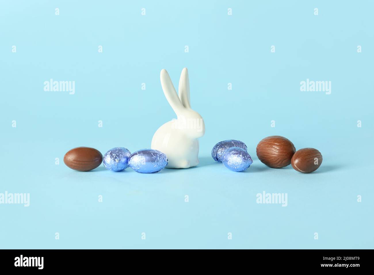 Chocolate Easter eggs and ceramic bunny on color background Stock Photo ...