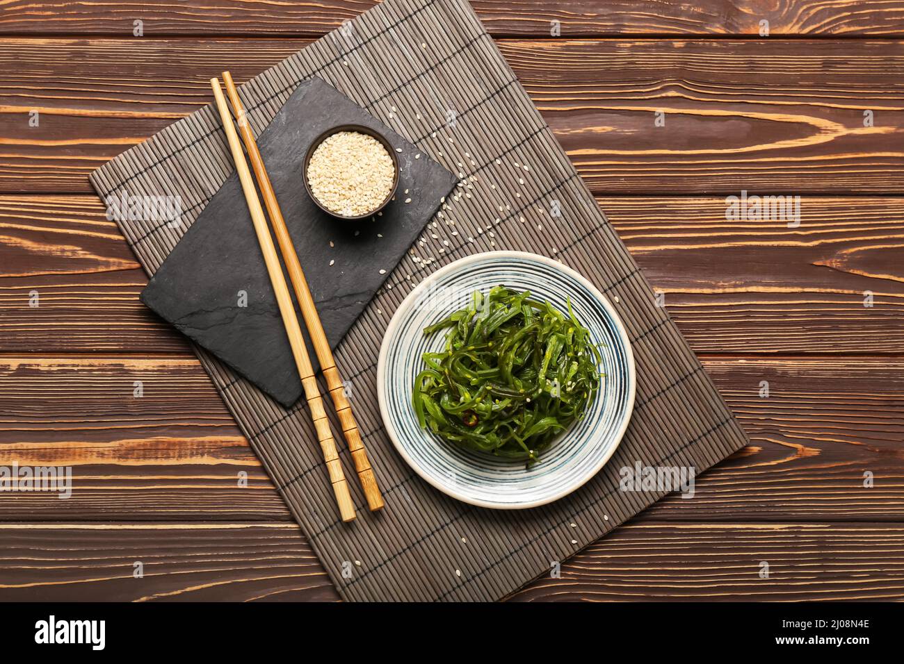 Plate with healthy seaweed salad and sesame on wooden background Stock ...