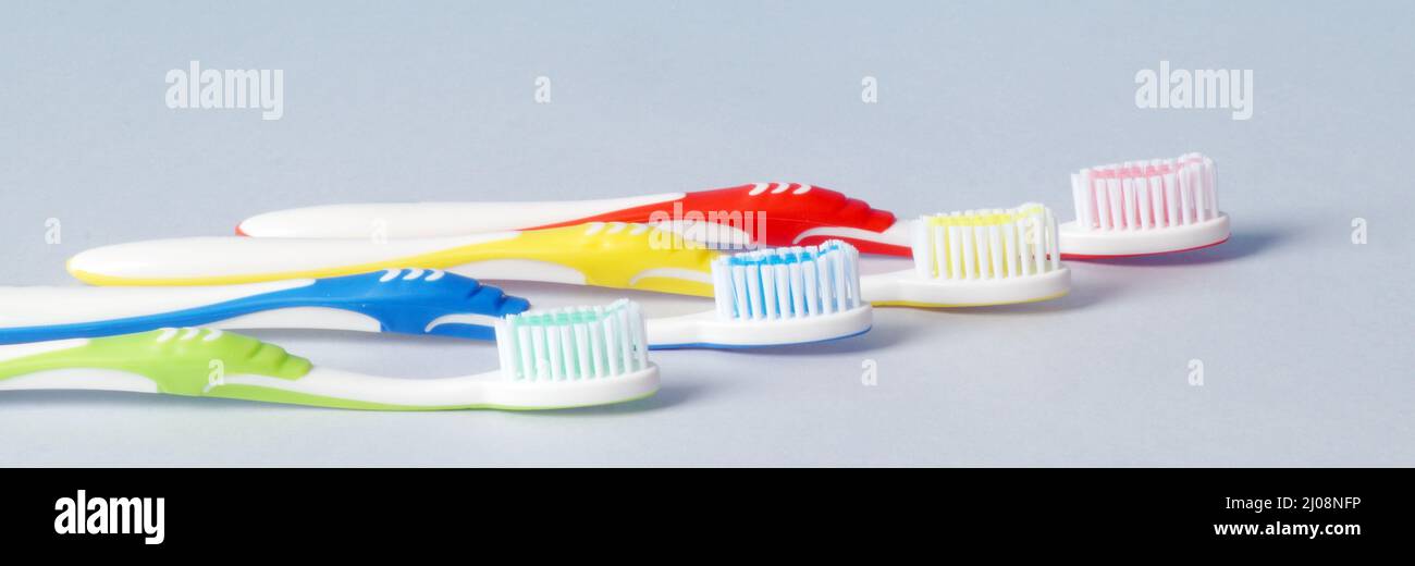 multi-colored toothbrushes are laid out one after another on the table ...