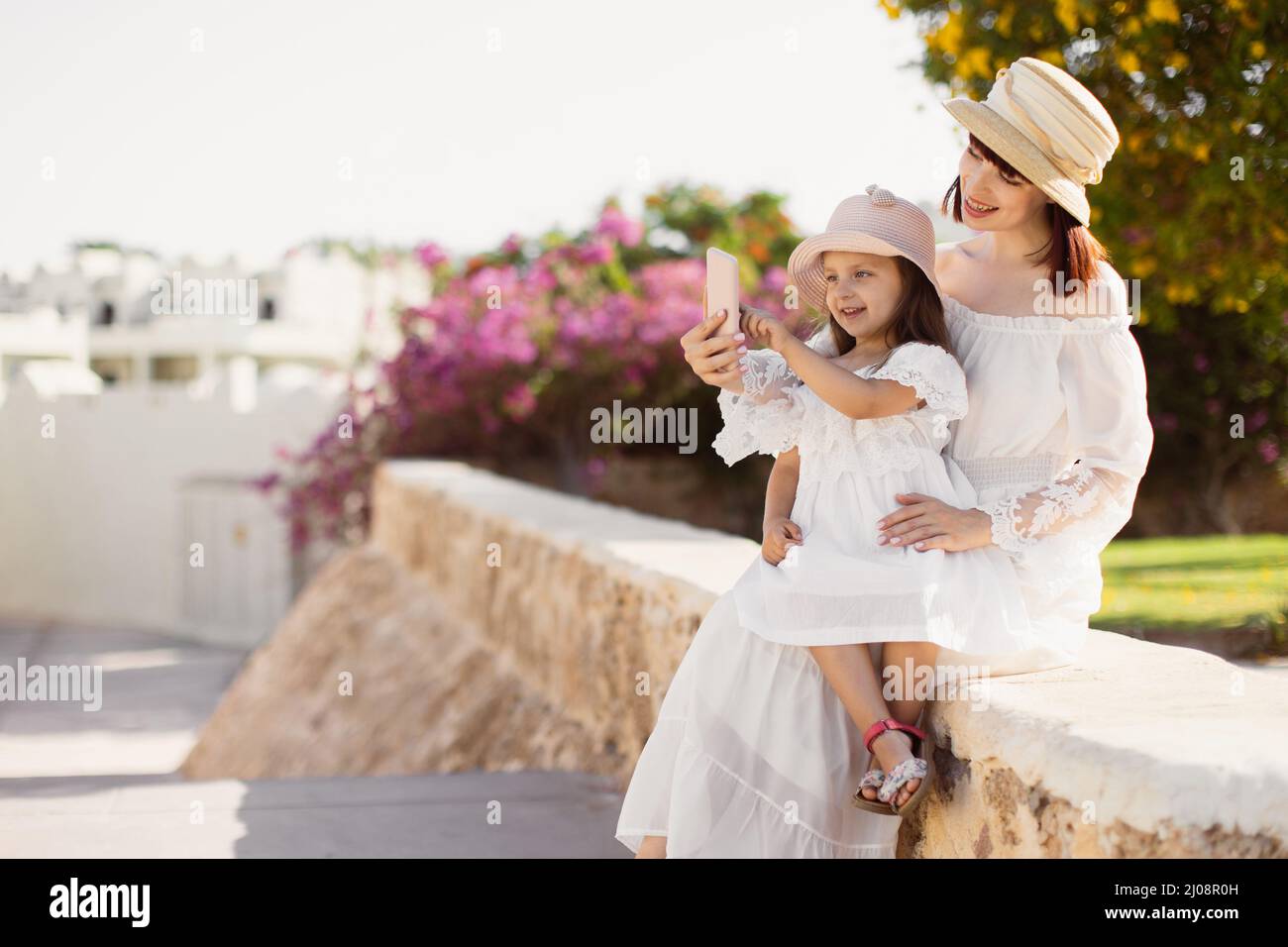 Portrait of good looking mother taking photo with daughter on mobile phone while sitting in the ...