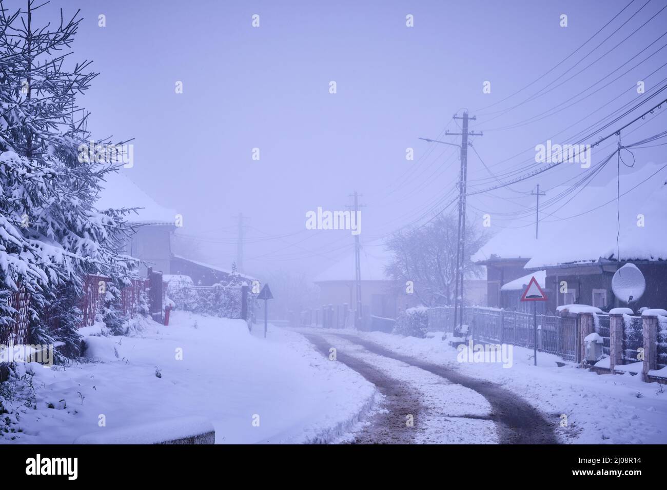 Snowy traffic road passing through the village with small houses on a ...