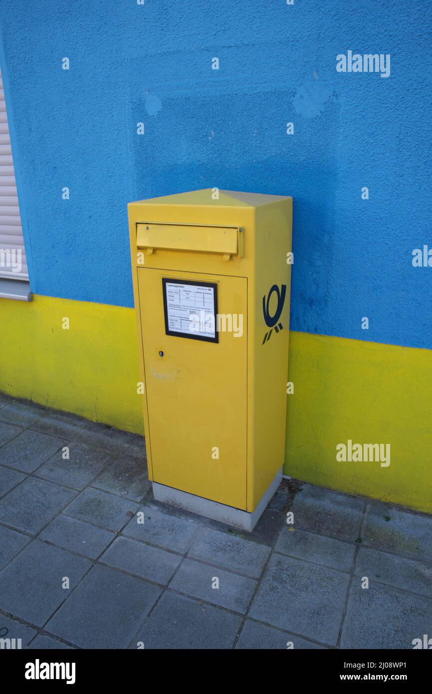 Single German post box in front of blue wall Stock Photo - Alamy