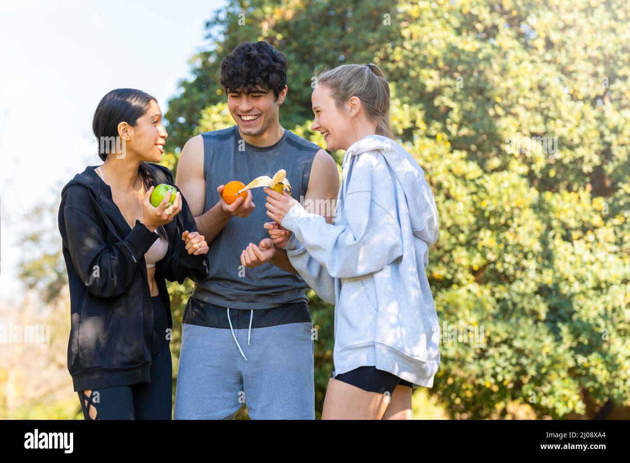 Young people doing sports are taking a break and eating some fruit in ...