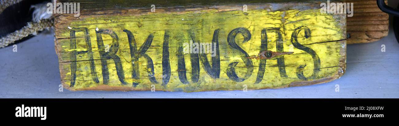 The state name Arkansas is handpainted on a long block of wood. Wood is ...