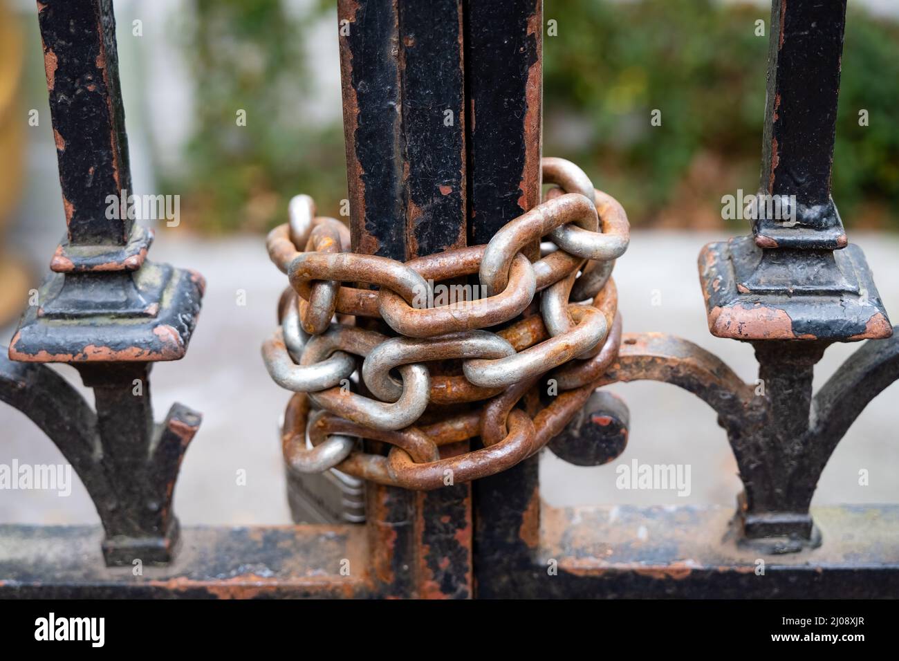 Heavy chain wrapped tightly around a weathered and rusting iron gate ...