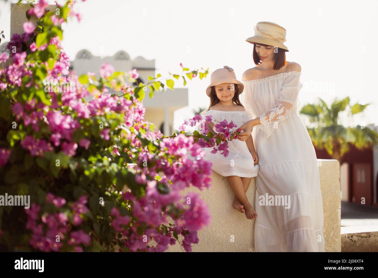 Lovely smiling lady with her daughter posing with strow hat sitting on ...