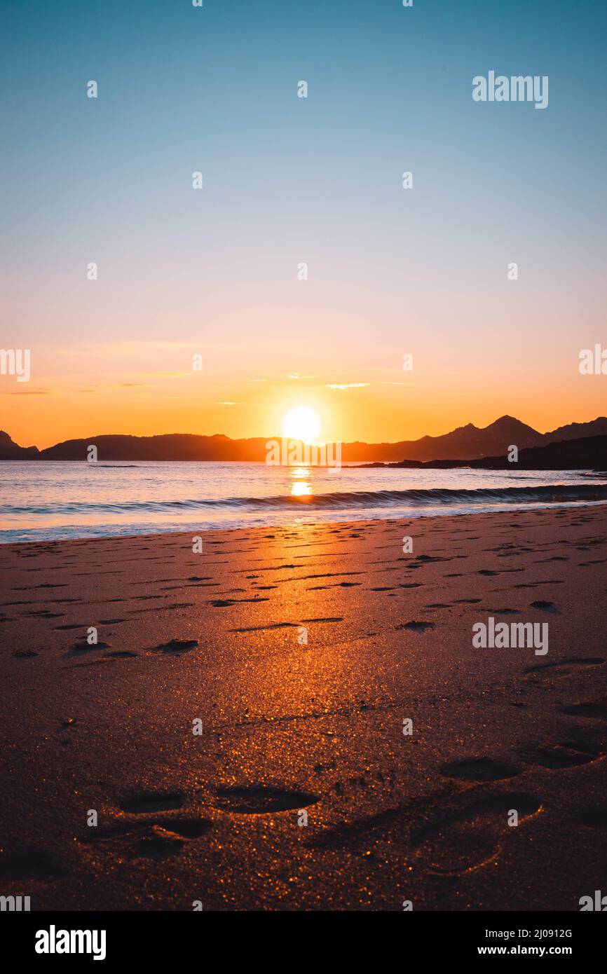 Vertical sunset shot over a sandy beach surrounded by mountains Stock ...