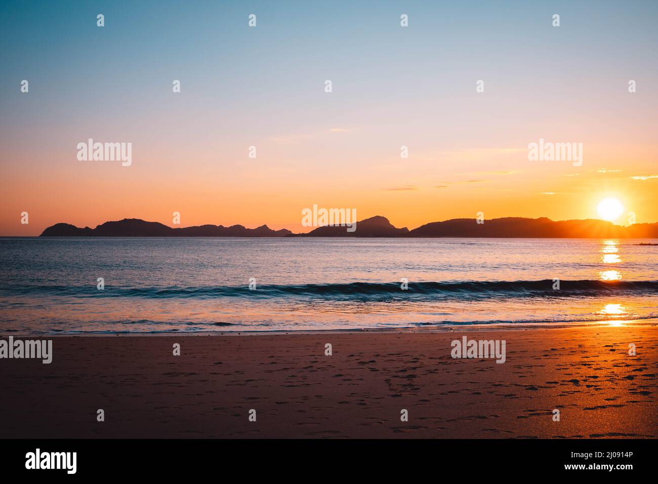 Sunset over a sandy beach surrounded by mountains Stock Photo - Alamy