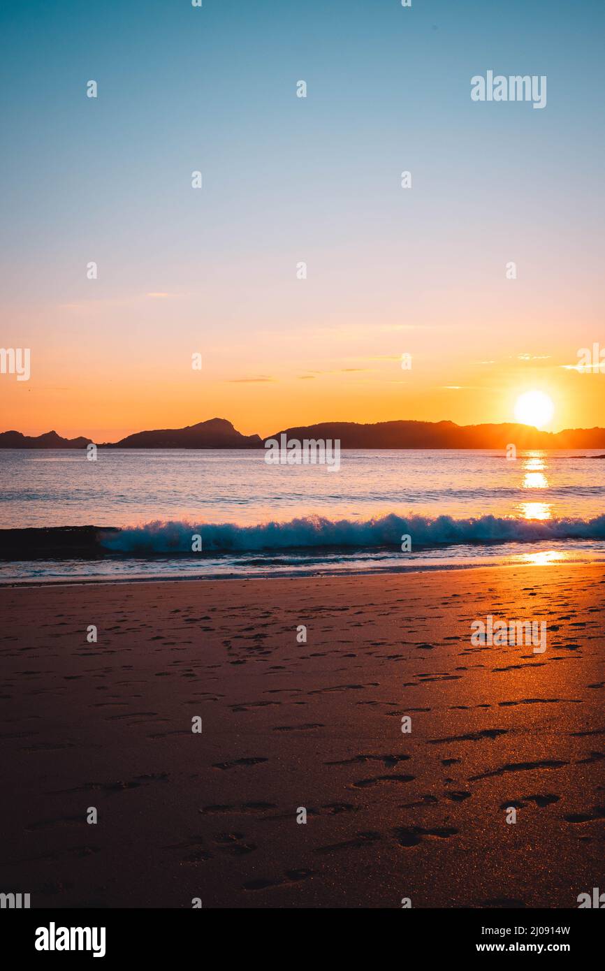 Vertical sunset shot over a sandy beach surrounded by mountains Stock ...