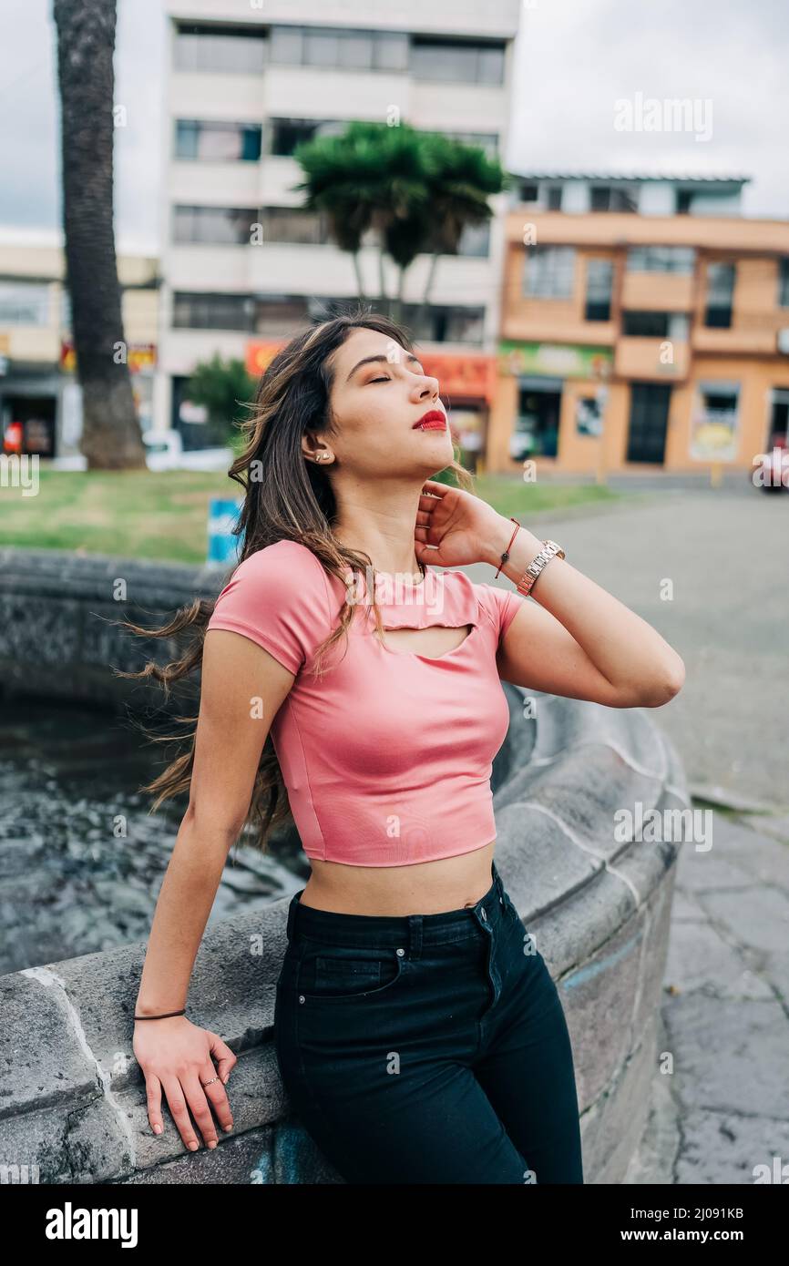 attractive young latin woman standing enjoying the sun in the day, wear ...