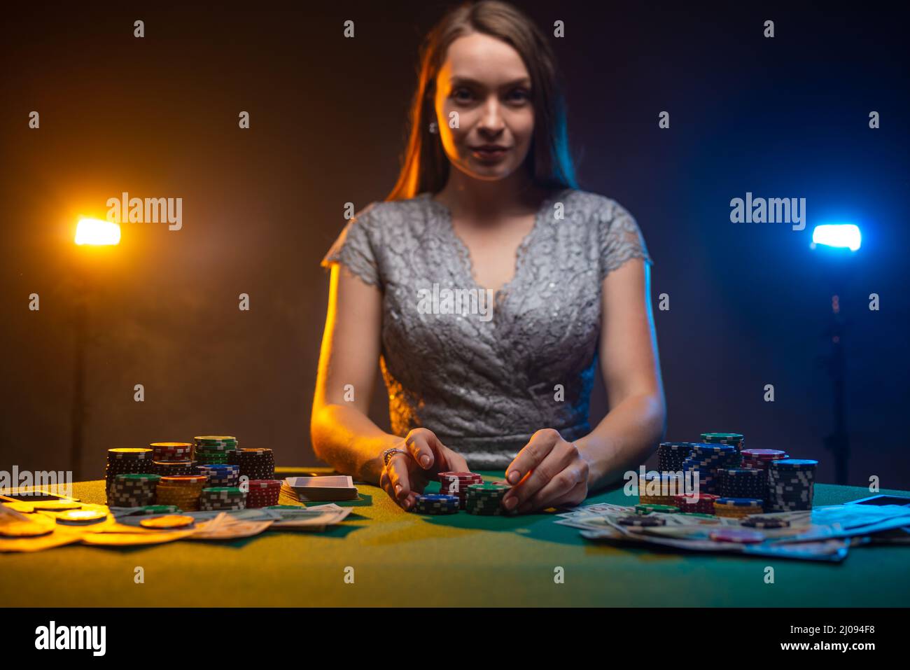 Beautiful smiling woman siting at the table in casino and play poker ...