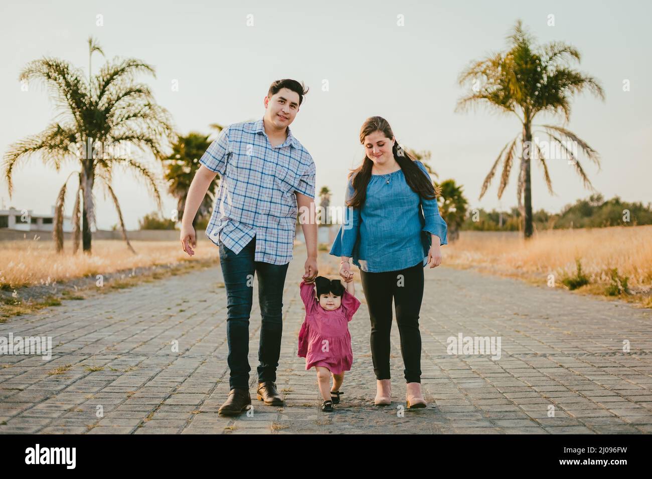 Hispanic family enjoying nature in the park - young parents with their ...