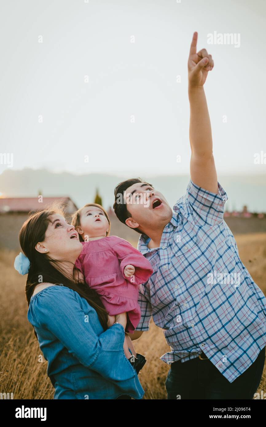 Hispanic family enjoying nature in the park - young parents with their ...