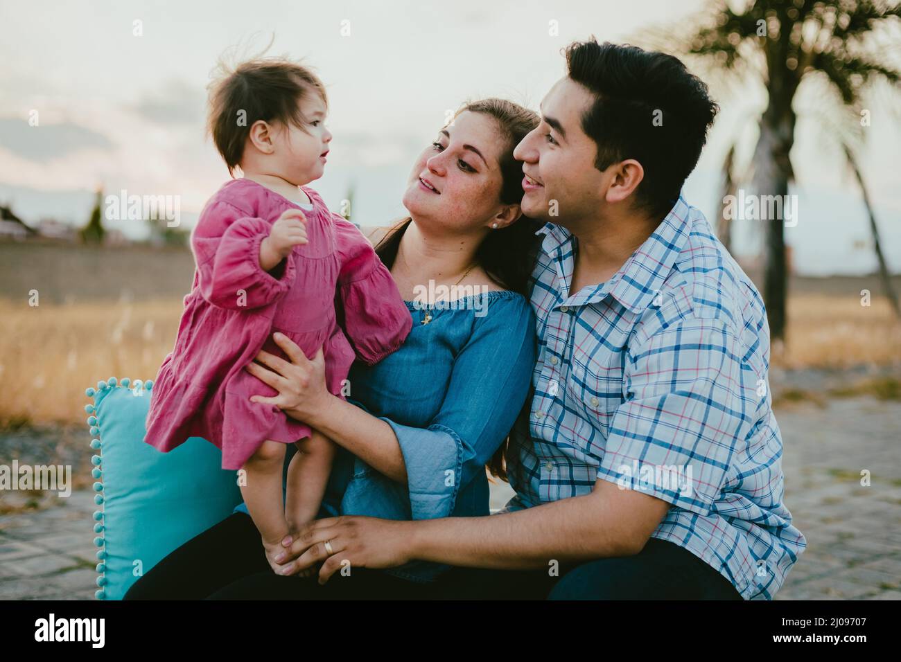 Hispanic family enjoying nature in the park - young parents with their ...