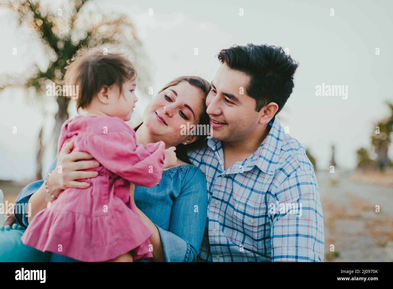 Hispanic family enjoying nature in the park - young parents with their ...