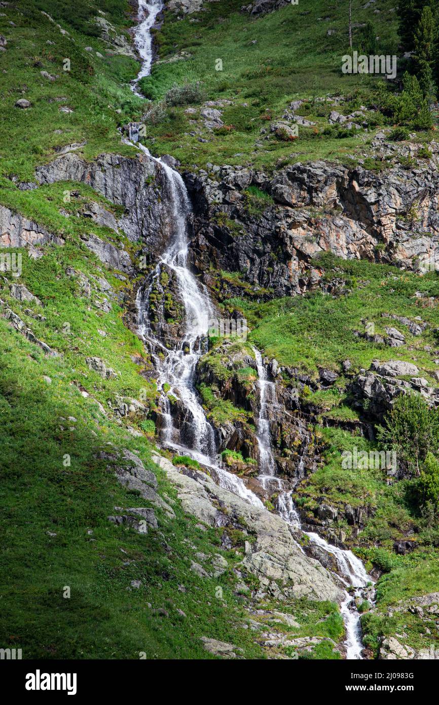 Cascading waterfall on the slope of a mountain range in the wilderness ...