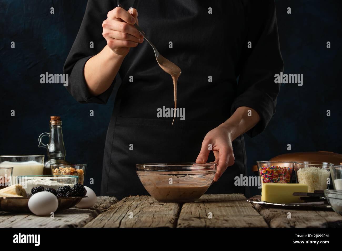 Pastry chef testing dough with a spoon. Backstage of cooking waffle on ...
