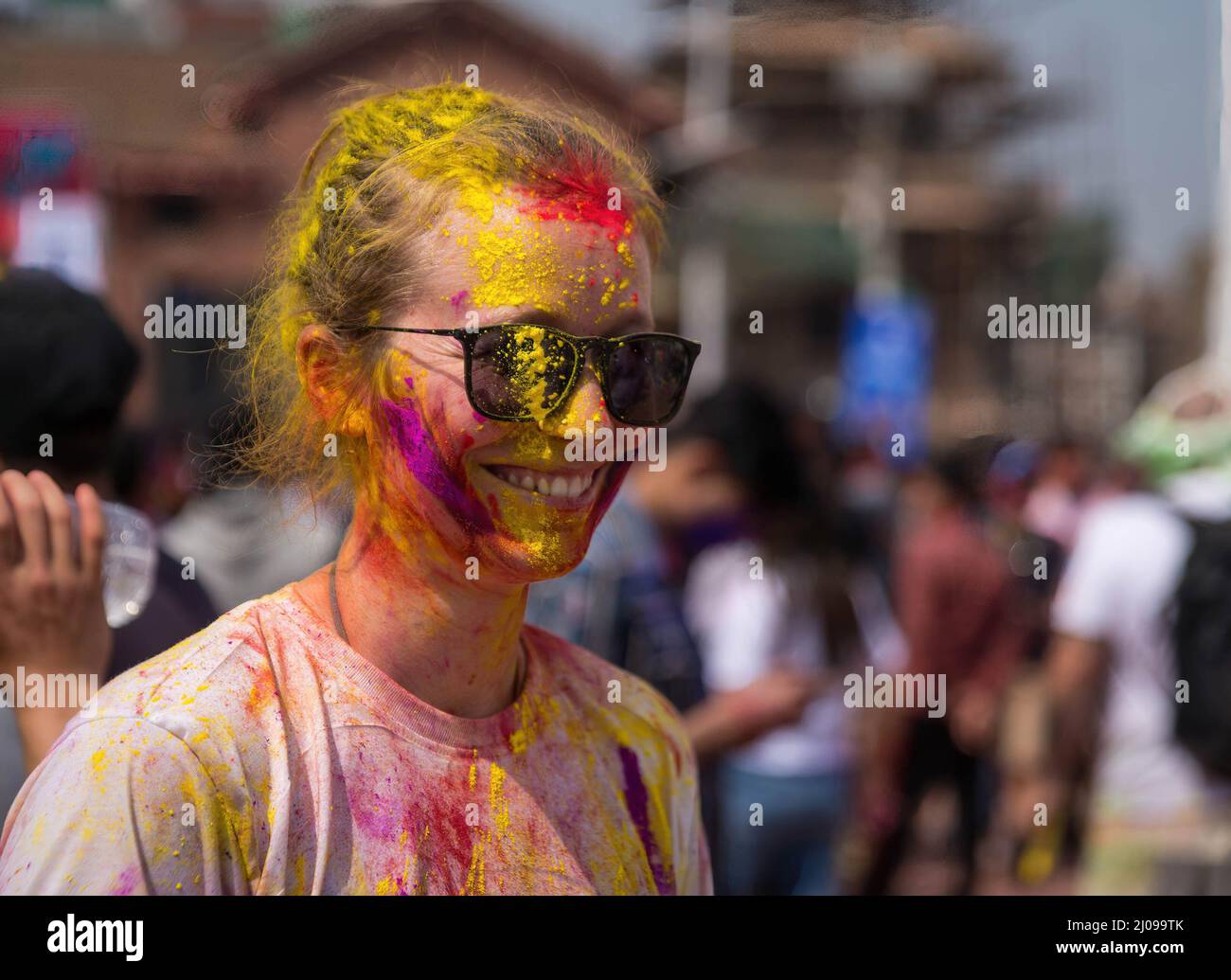 A woman smeared with vermilion powder smiles during the festival. The ...