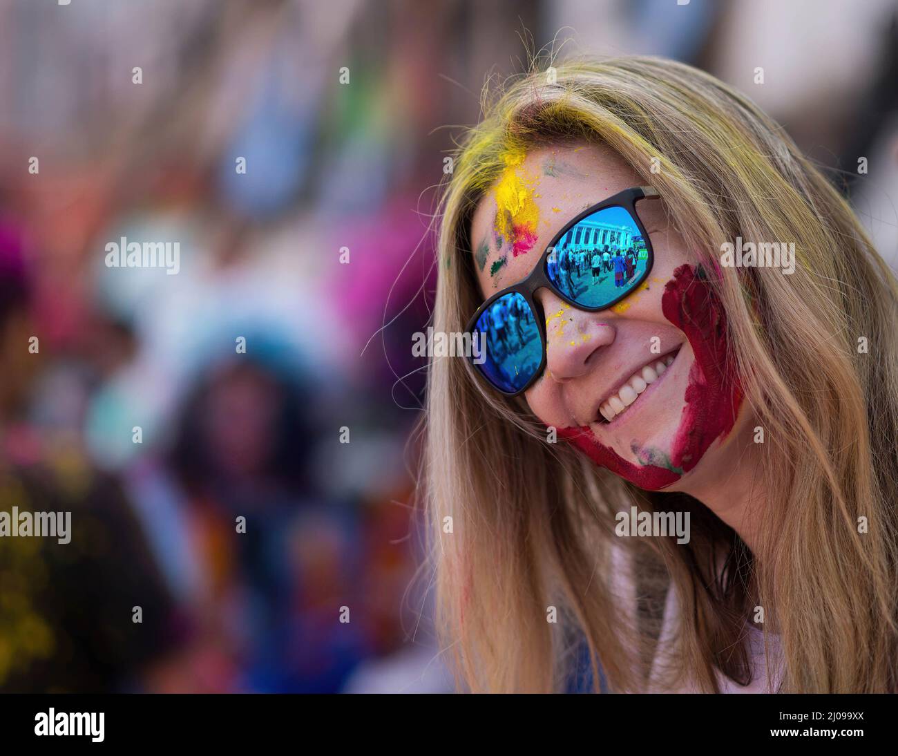 A woman smeared with vermilion powder smiles during the festival. The ...