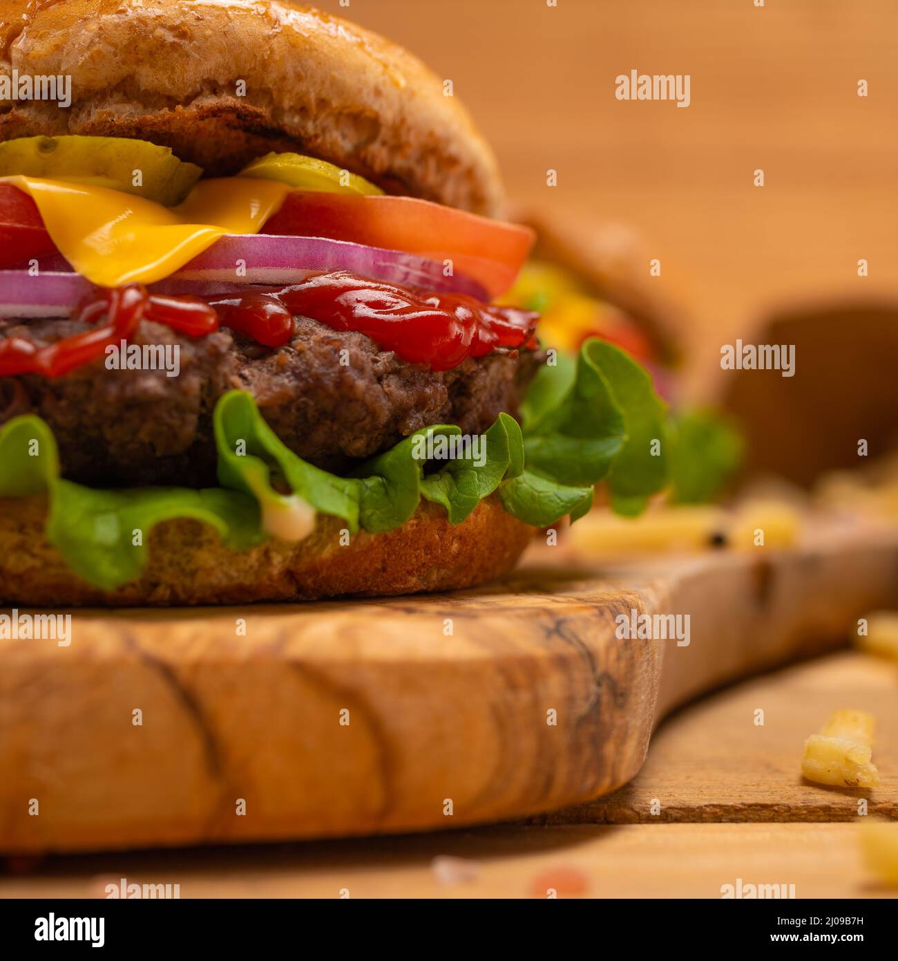 Macro shot view of big appetizing burger with bacon wooden board ...
