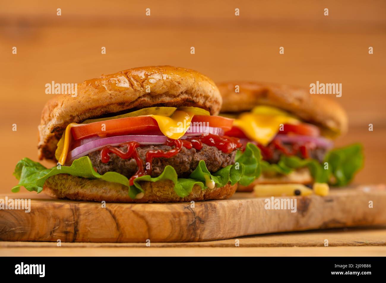 Appetizing burgers with bacon wooden board against beige background ...