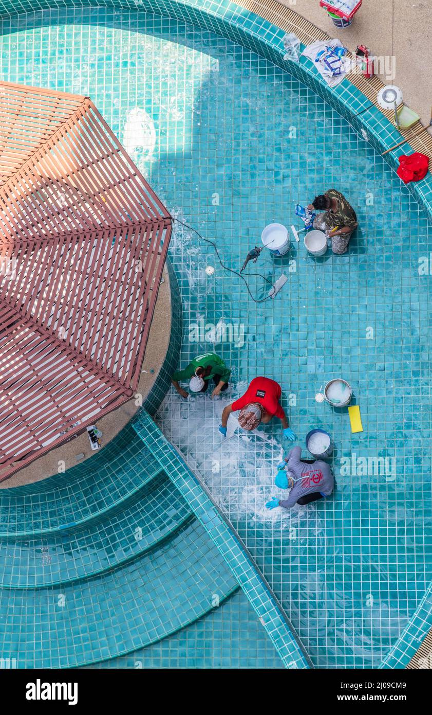 Top view of workers tiling the floor of a swimming pool at a ...