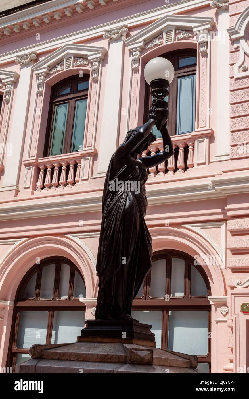 A statue holding a lamp against a historical building in Lima, Peru ...