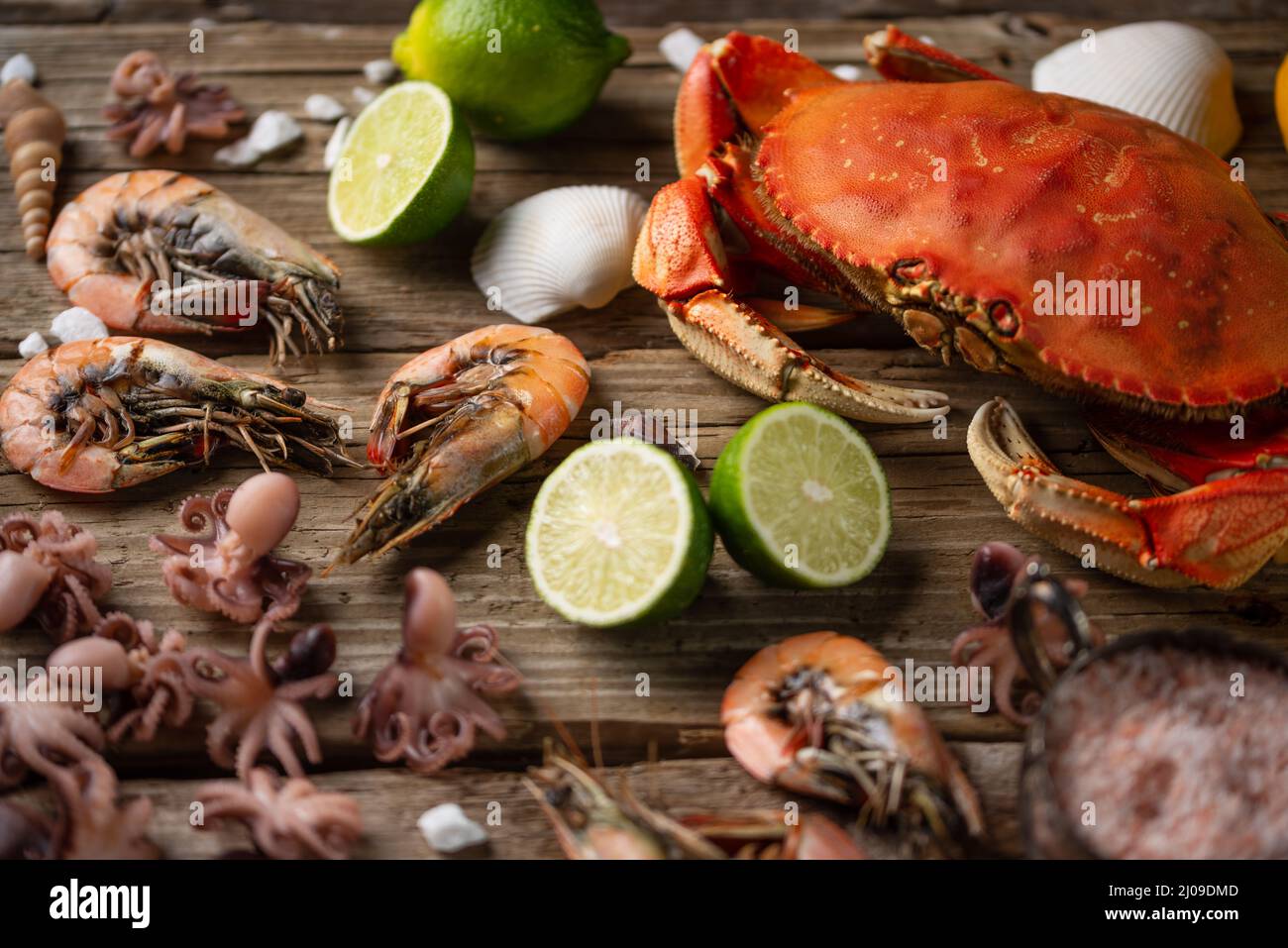 Assorted seafood served with lime and seashells on rustic wooden ...
